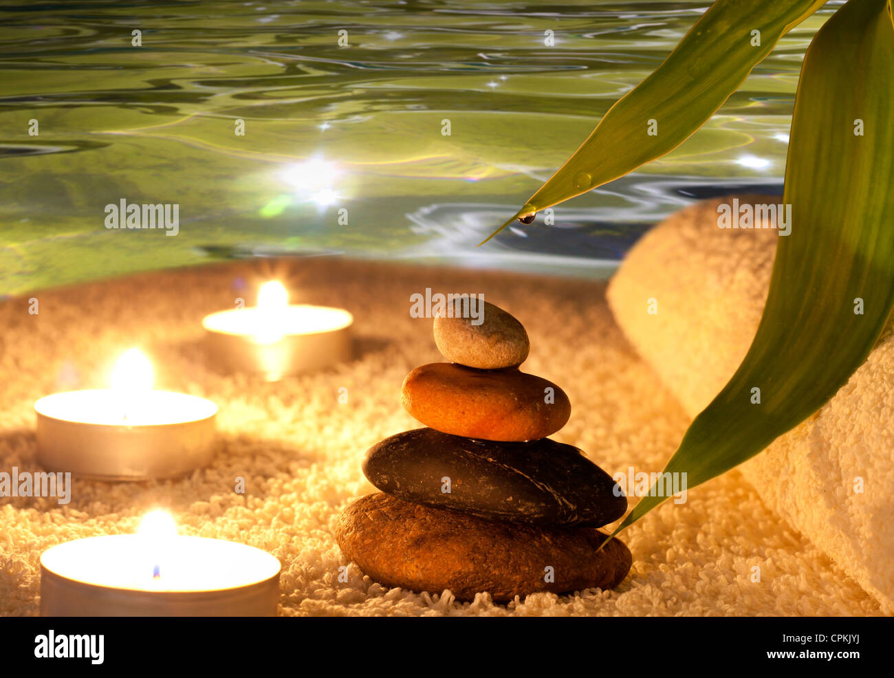 spa stones with candles and water on the towel Stock Photo - Alamy