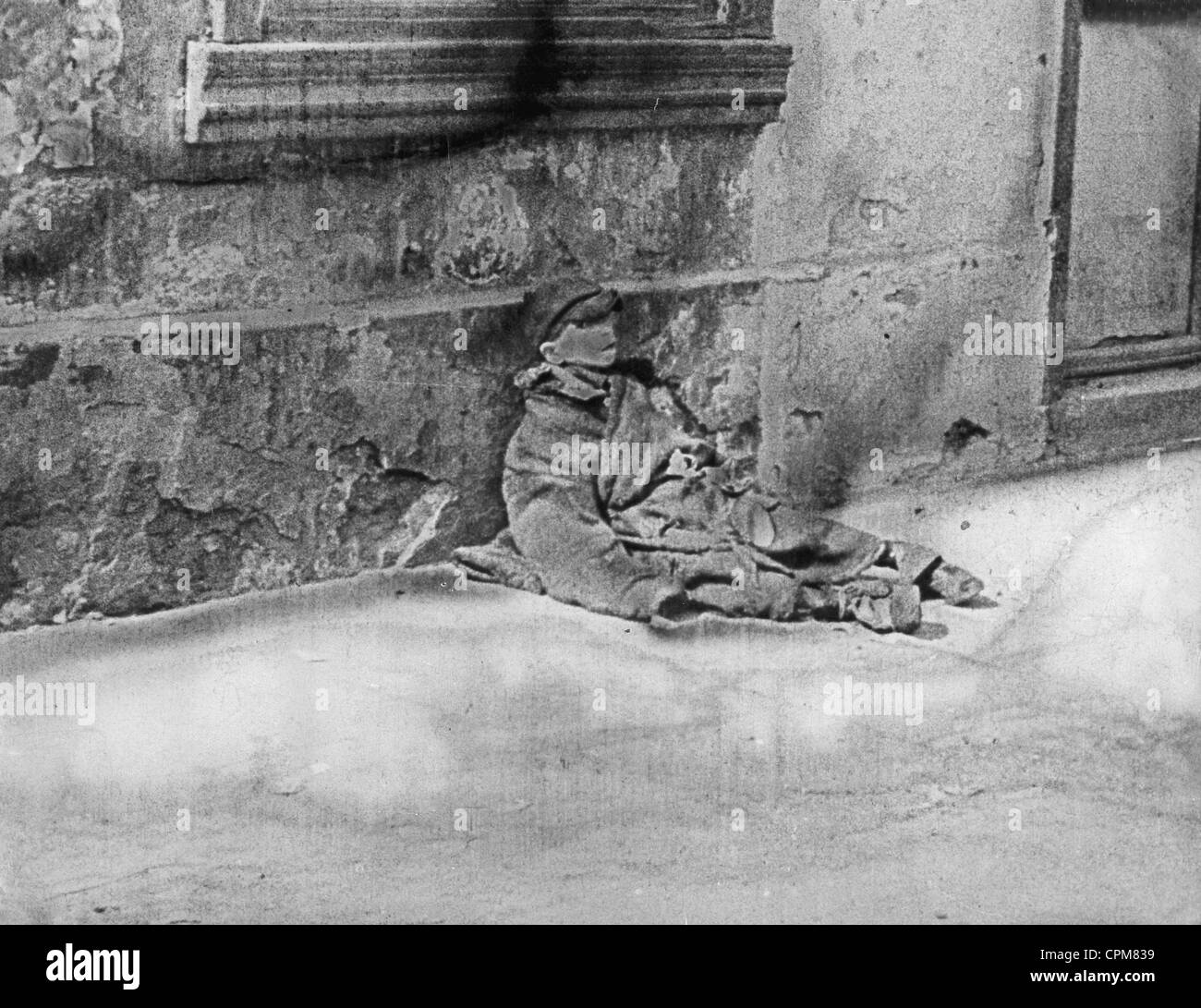 The dead body of a starved Jewish boy leaning against the wall of a ...