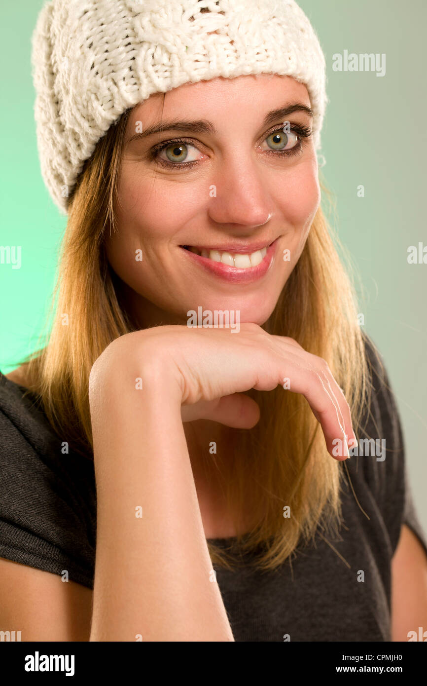 portrait of a happy woman with a winter cap in front of green ...