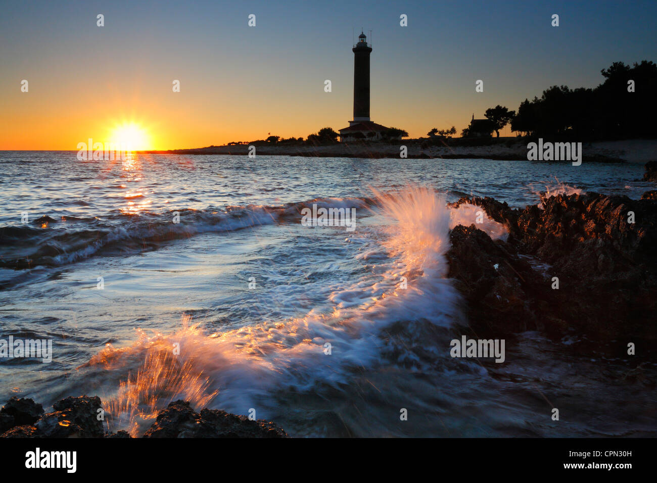 Sunset at Veli rat on "Dugi otok", Croatia. Waves splashing rocks on ...