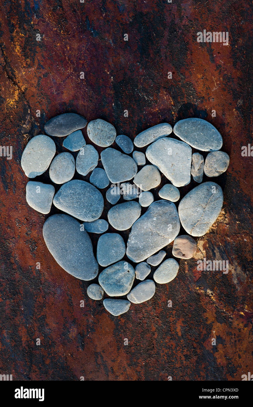 Heart shape pebbles on a texture slate background Stock Photo - Alamy
