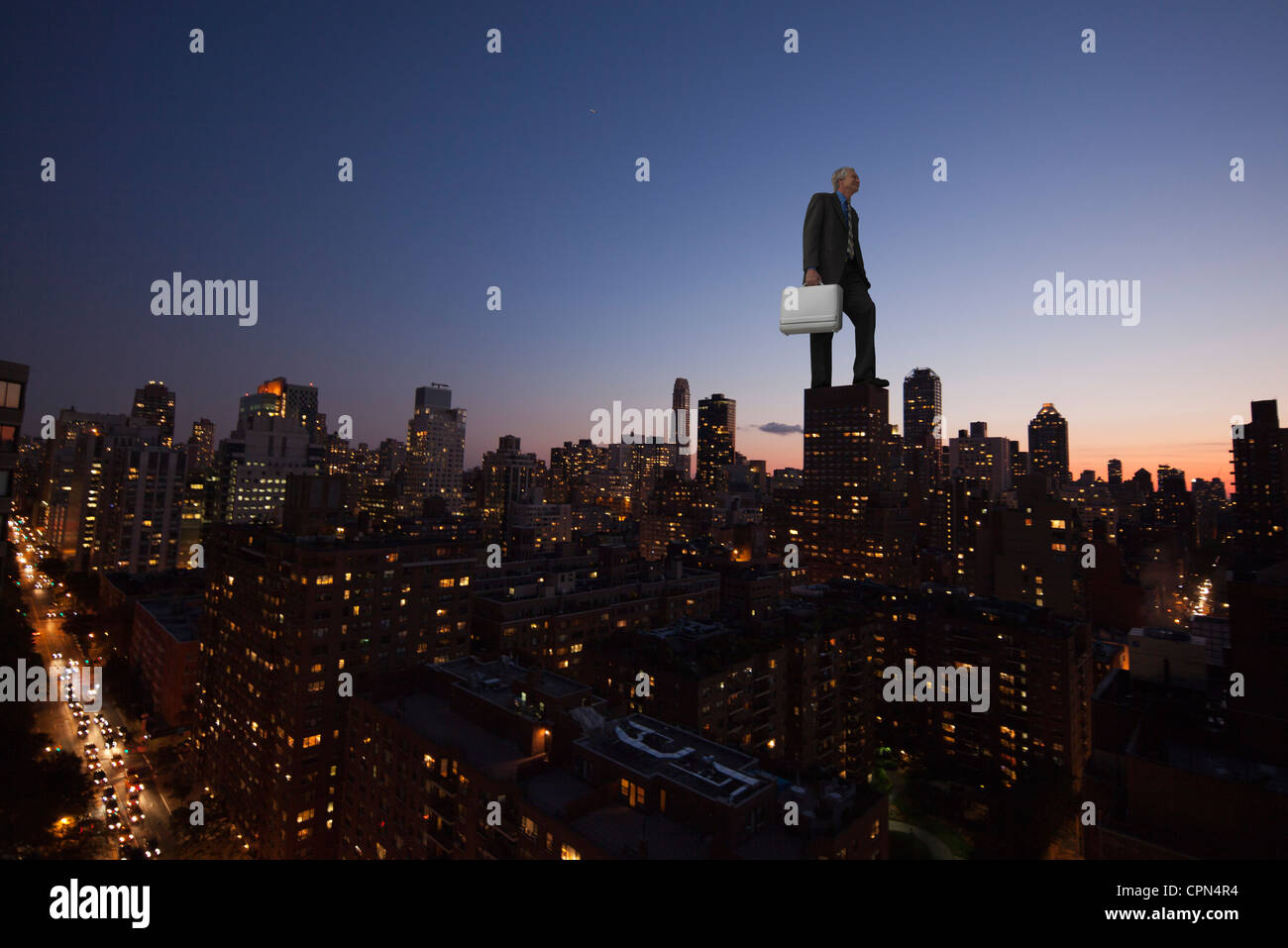 Giant businessman standing on top of skyscraper at dusk Stock Photo - Alamy