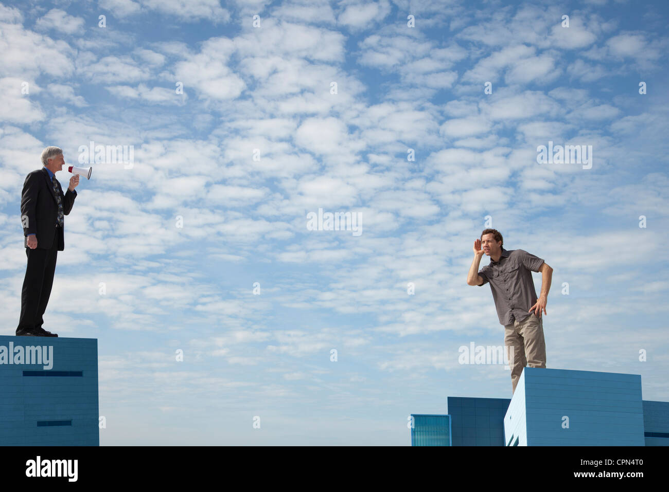 Oversized men standing on rooftops, one speaking through megaphone ...