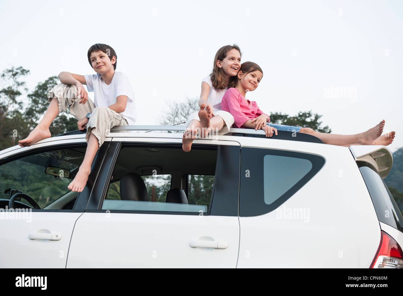 Sibling sitting together on roof of car Stock Photo - Alamy