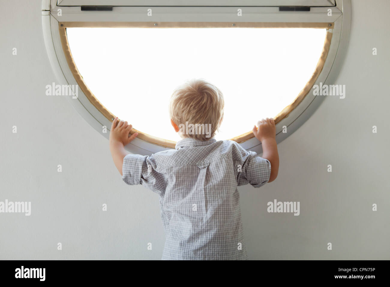 Little boy looking through window, rear view Stock Photo - Alamy