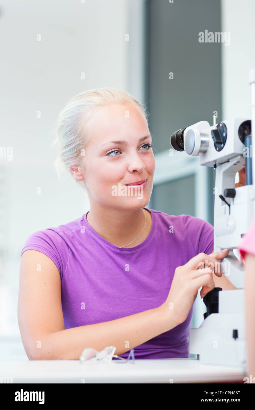 optometry concept - portrait of a young pretty optometrist using slit ...
