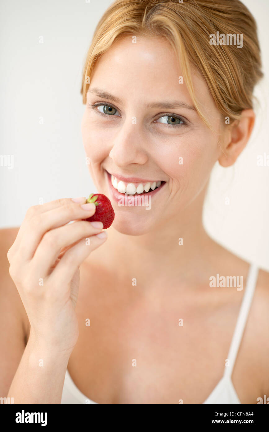 Young woman eating strawberry, portrait Stock Photo - Alamy