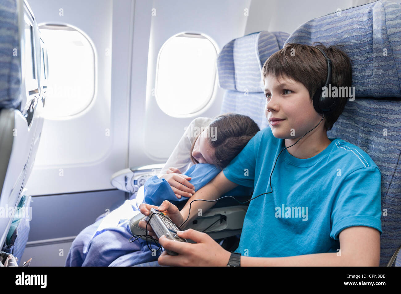 Boy using remote control to change channels on airplane Stock Photo - Alamy