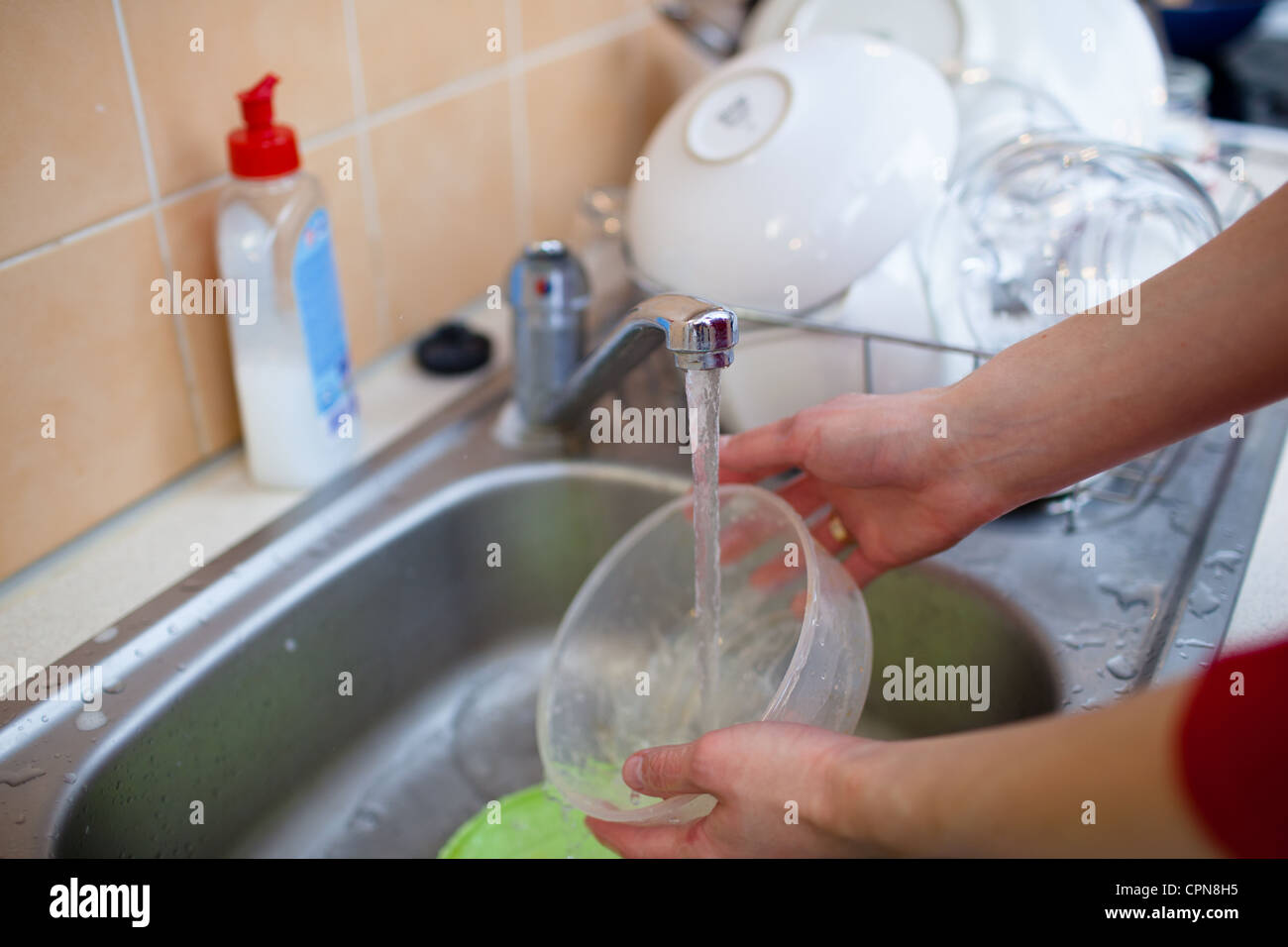 Washing of the dishes - woman hands rinsing dishes under running water ...