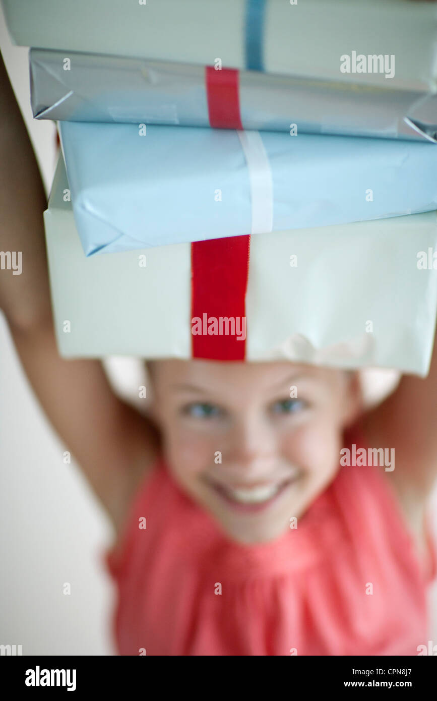 Girl holding stack of gifts on head Stock Photo - Alamy