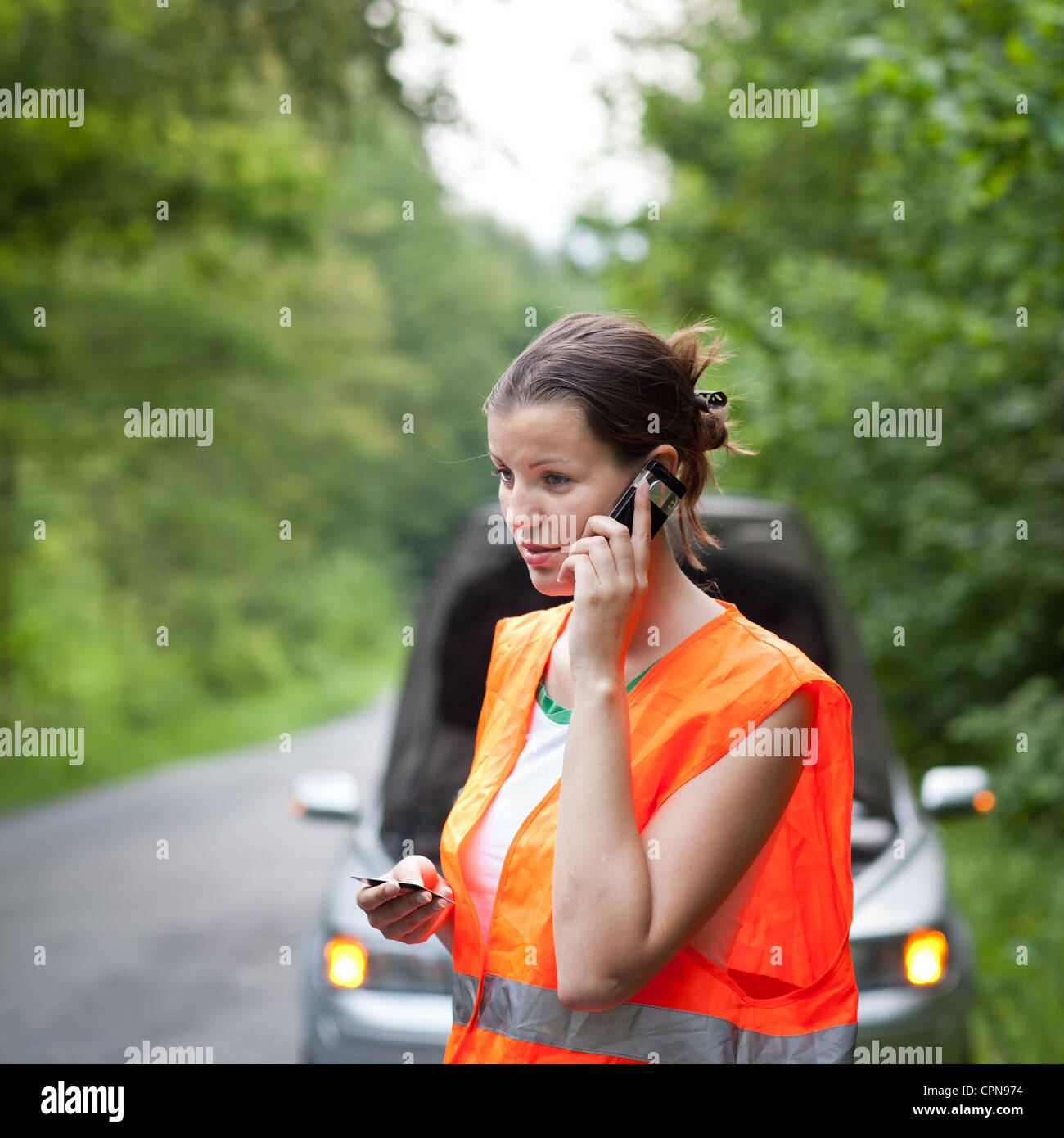 Young female driver wearing a high visibility vest, calling the ...