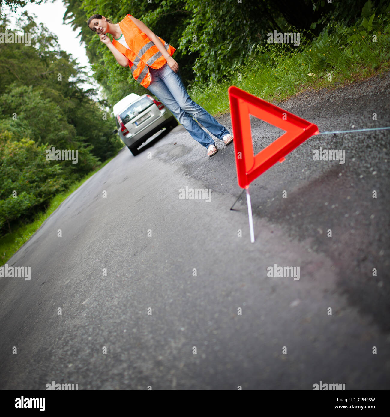 Young female driver wearing a high visibility vest, calling the ...
