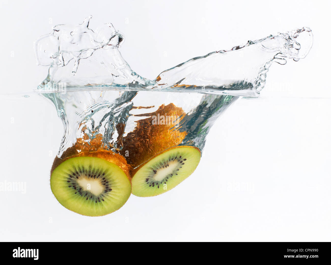 Kiwi halves splashing into water Stock Photo - Alamy