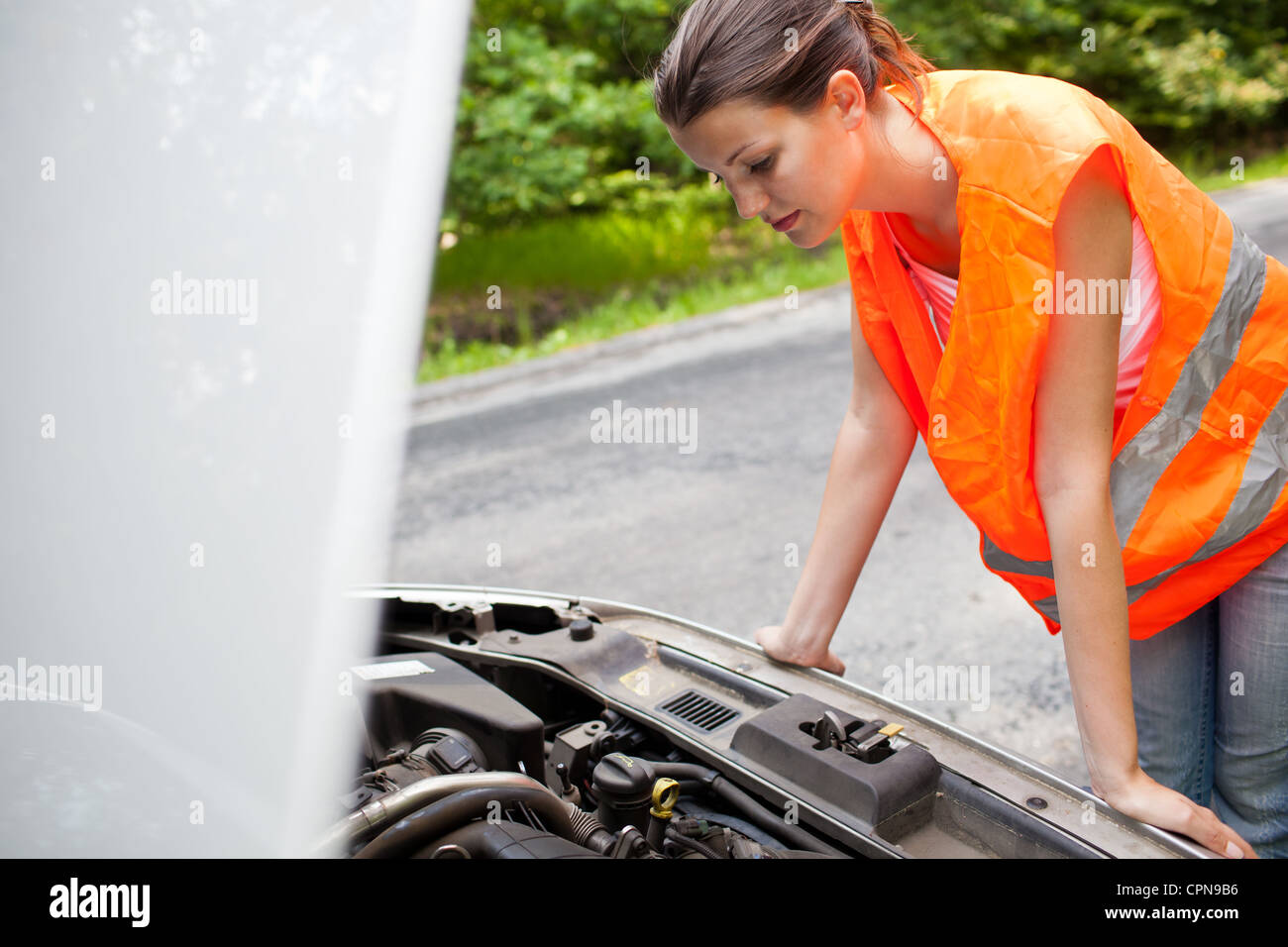 Young female driver wearing a high visibility vest, bending over the ...