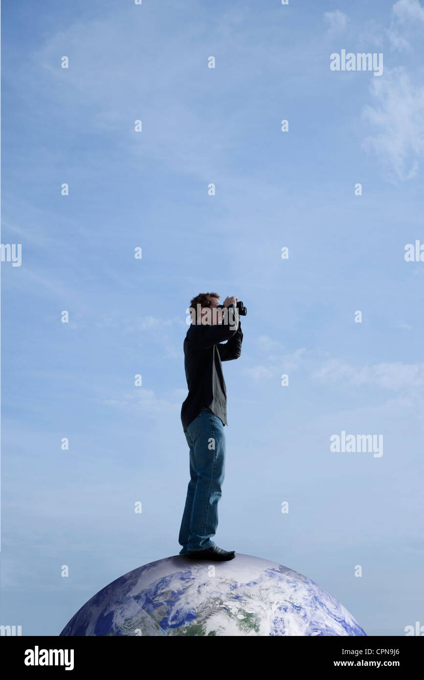 Man standing on top of the world, looking through binoculars Stock ...