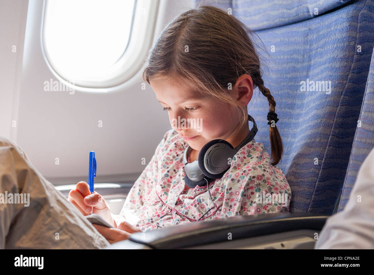 Girl writing in notebook on airplane Stock Photo - Alamy