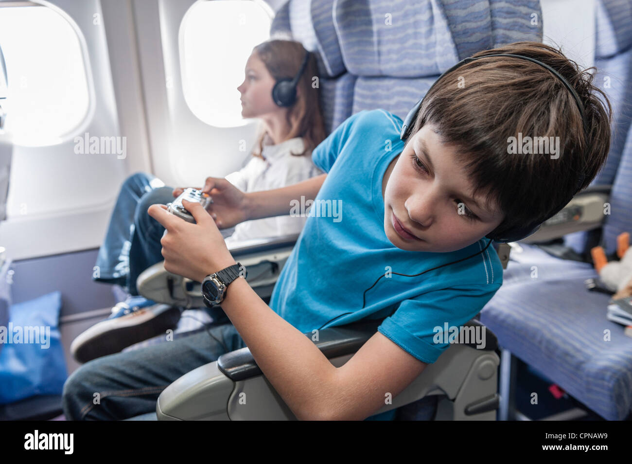 Boy leaning out of seat on airplane to look down aisle Stock Photo - Alamy