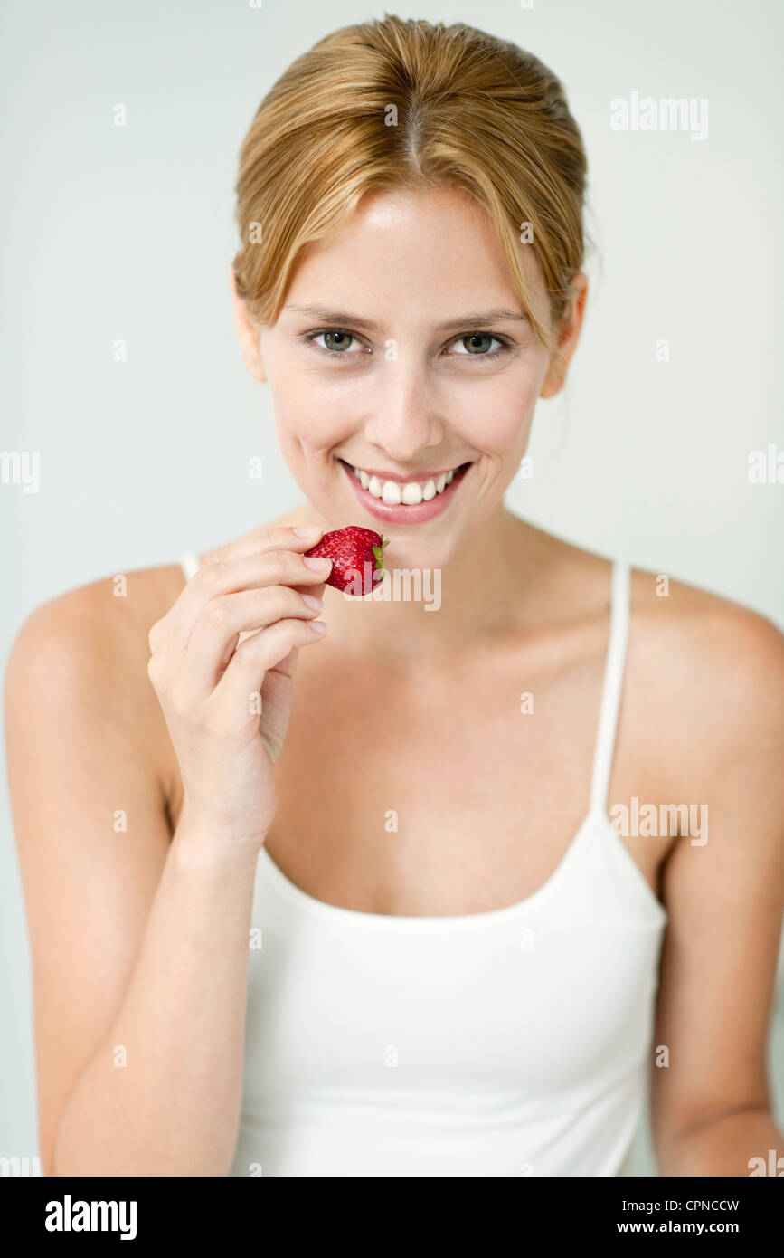 Young woman eating strawberry, portrait Stock Photo - Alamy
