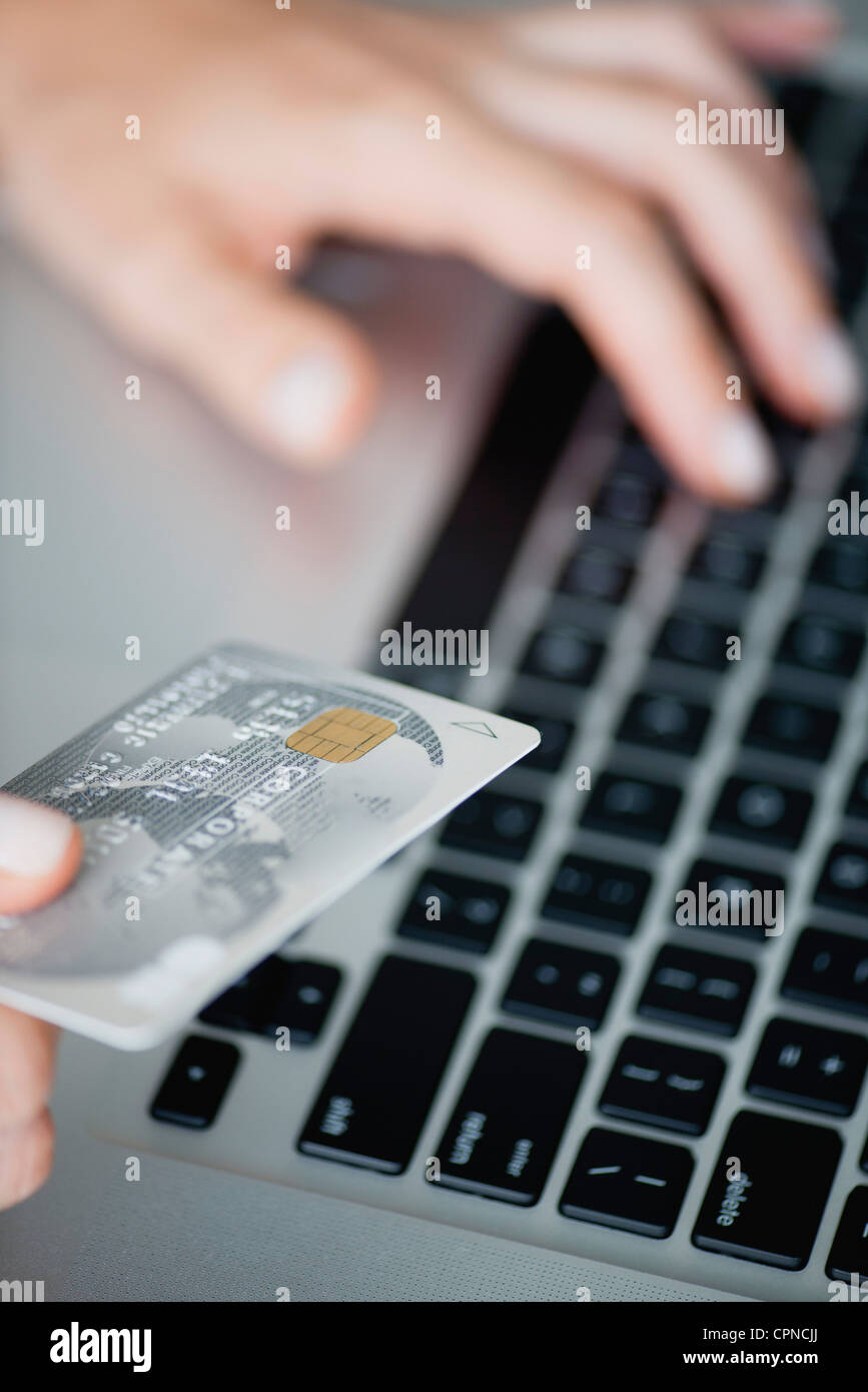 Woman holding credit card while using laptop computer, cropped Stock ...