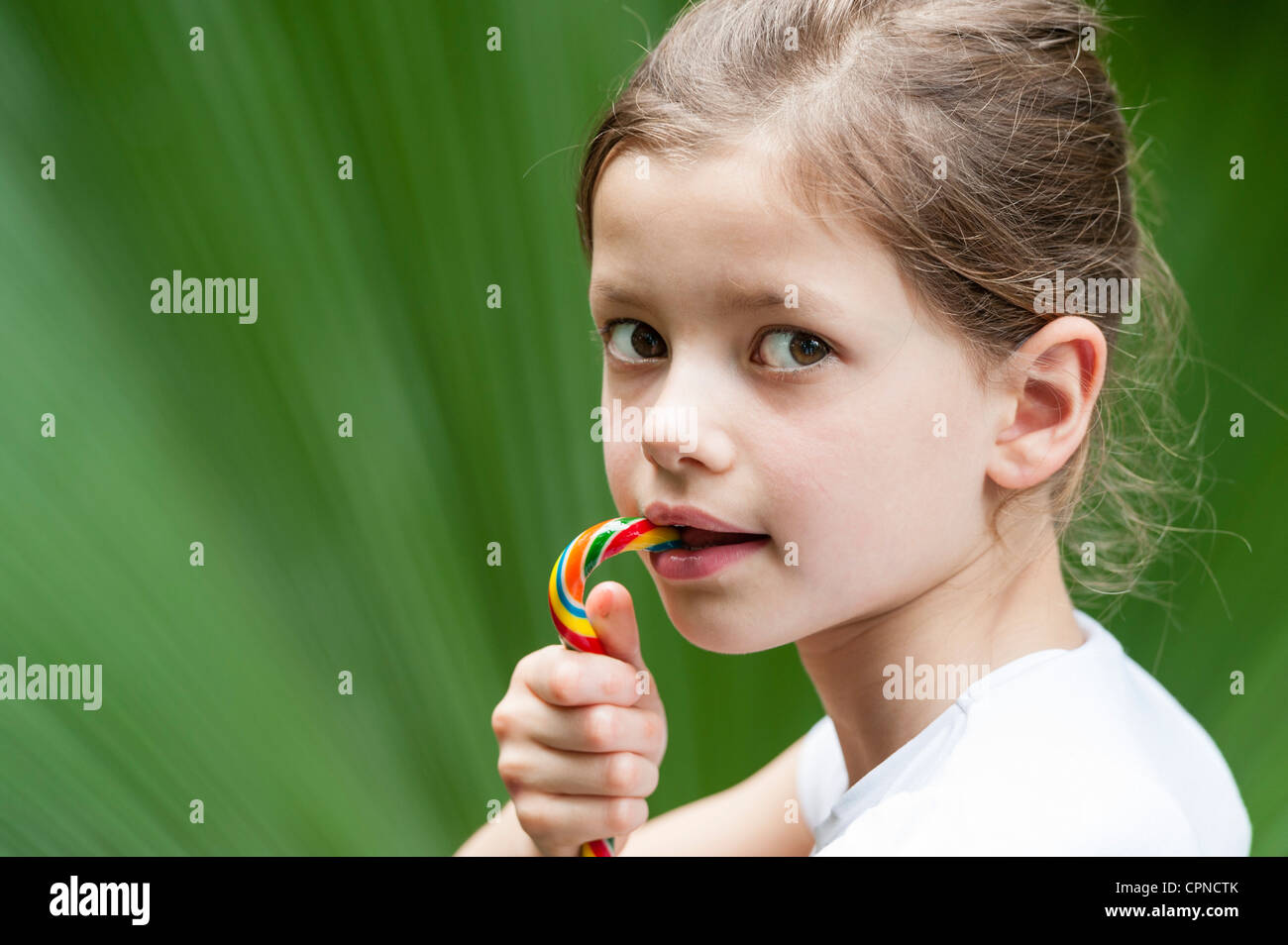 Girl eating candy, looking over shoulder Stock Photo - Alamy