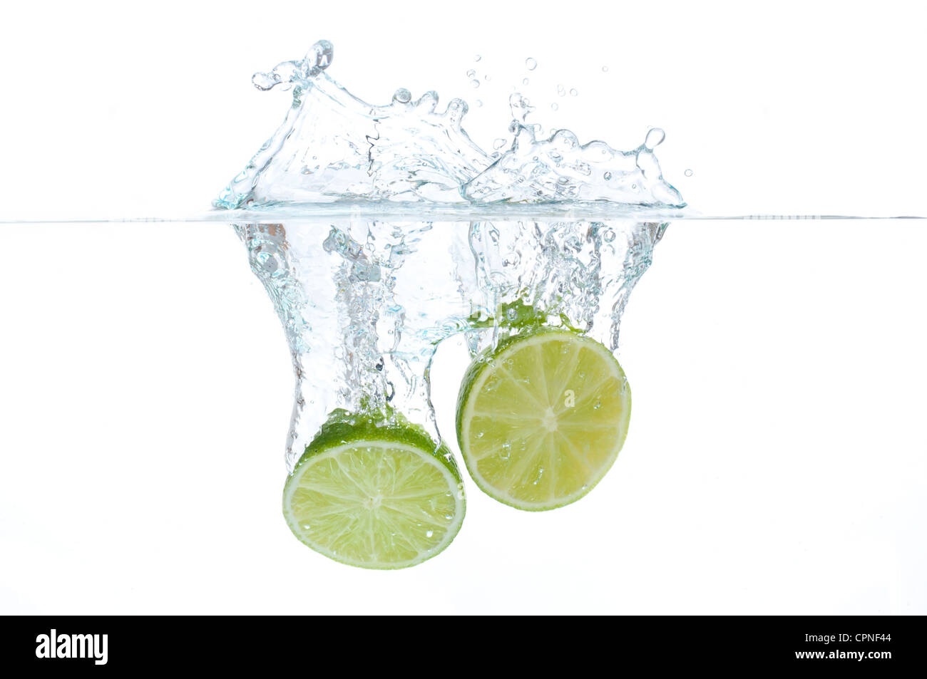 Lime halves splashing into water Stock Photo - Alamy
