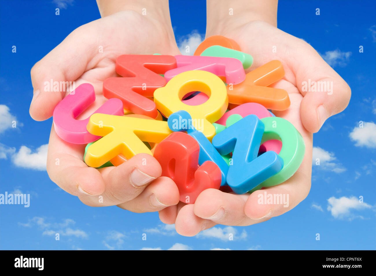 hands with alphabet on blue sky background Stock Photo - Alamy