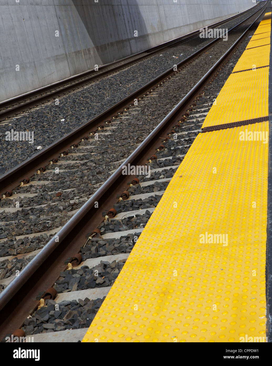 Diminishing straight train tracks at station with yellow boarding area ...