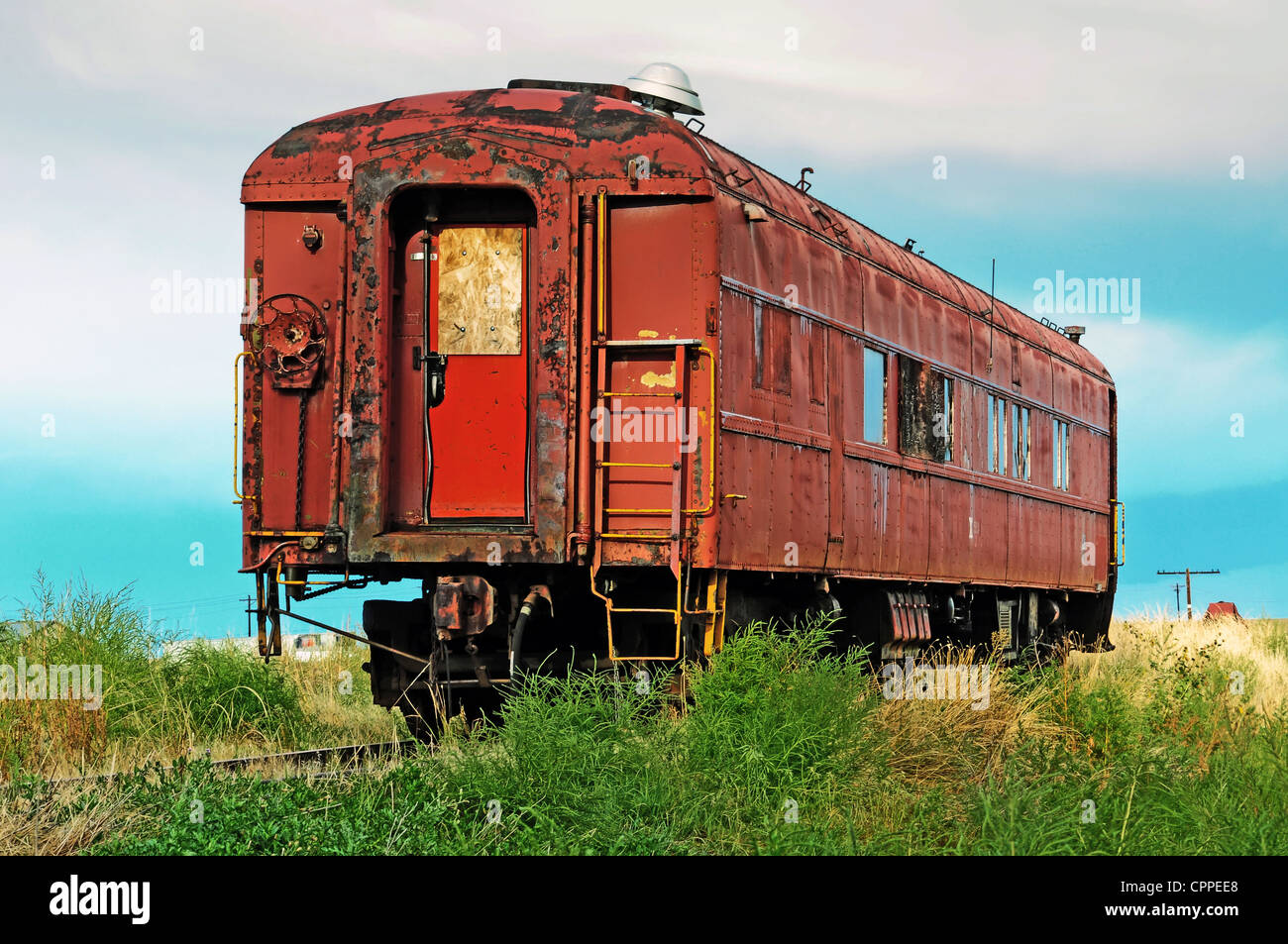 Rusted and worn out, an old passenger railcar sits on a rail siding ...