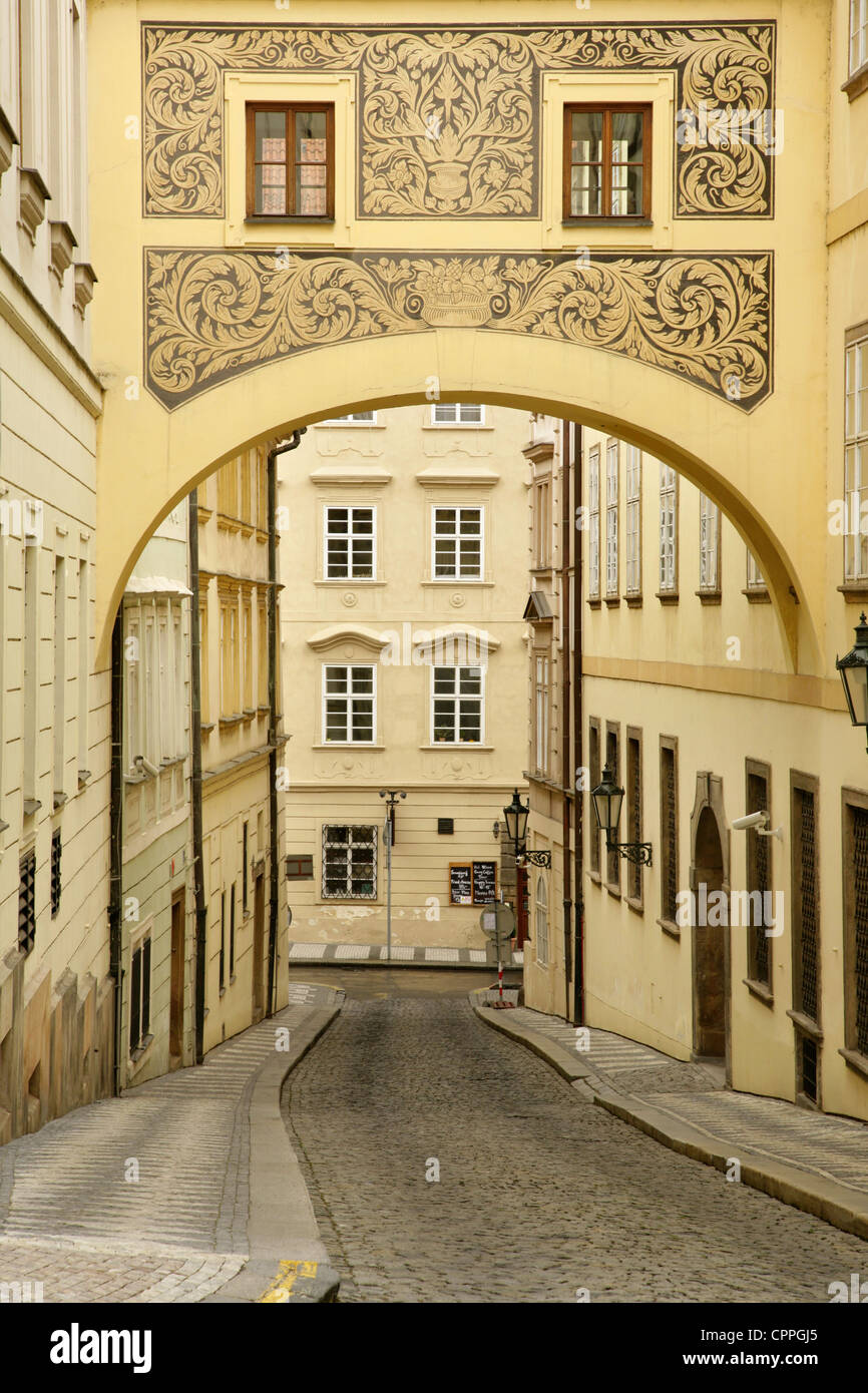 Ornate buildings and archway across cobbled street in the Mala Strana ...