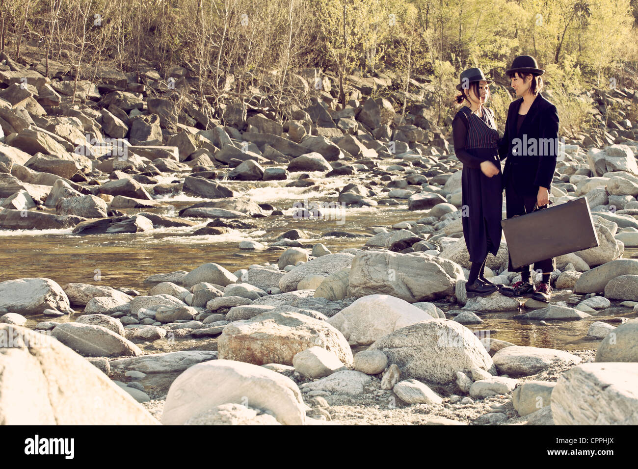 a man and a woman standing on rocks surrounded by a mountain stream ...