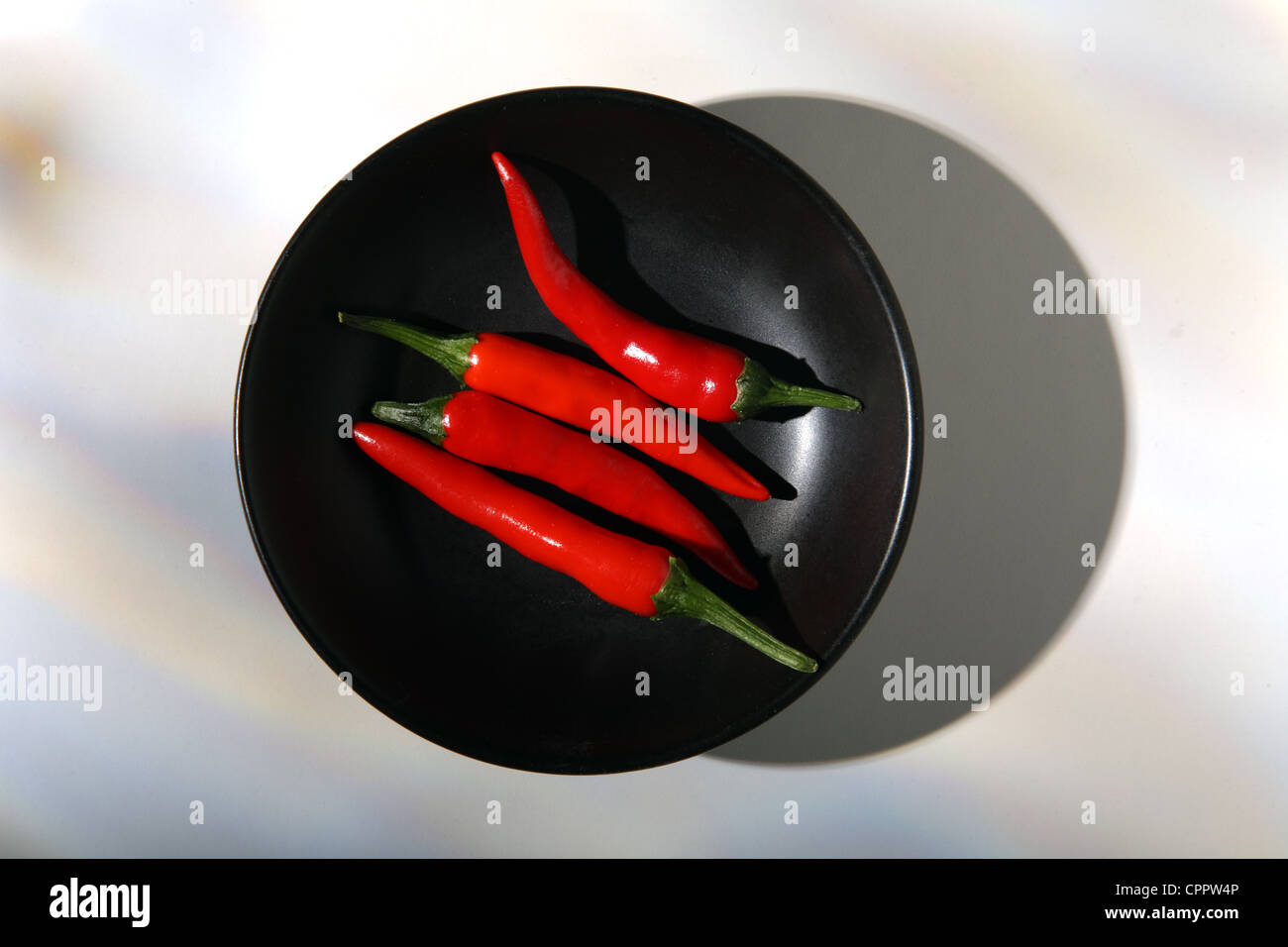 Four red Thai Chilies on a black plate Stock Photo - Alamy