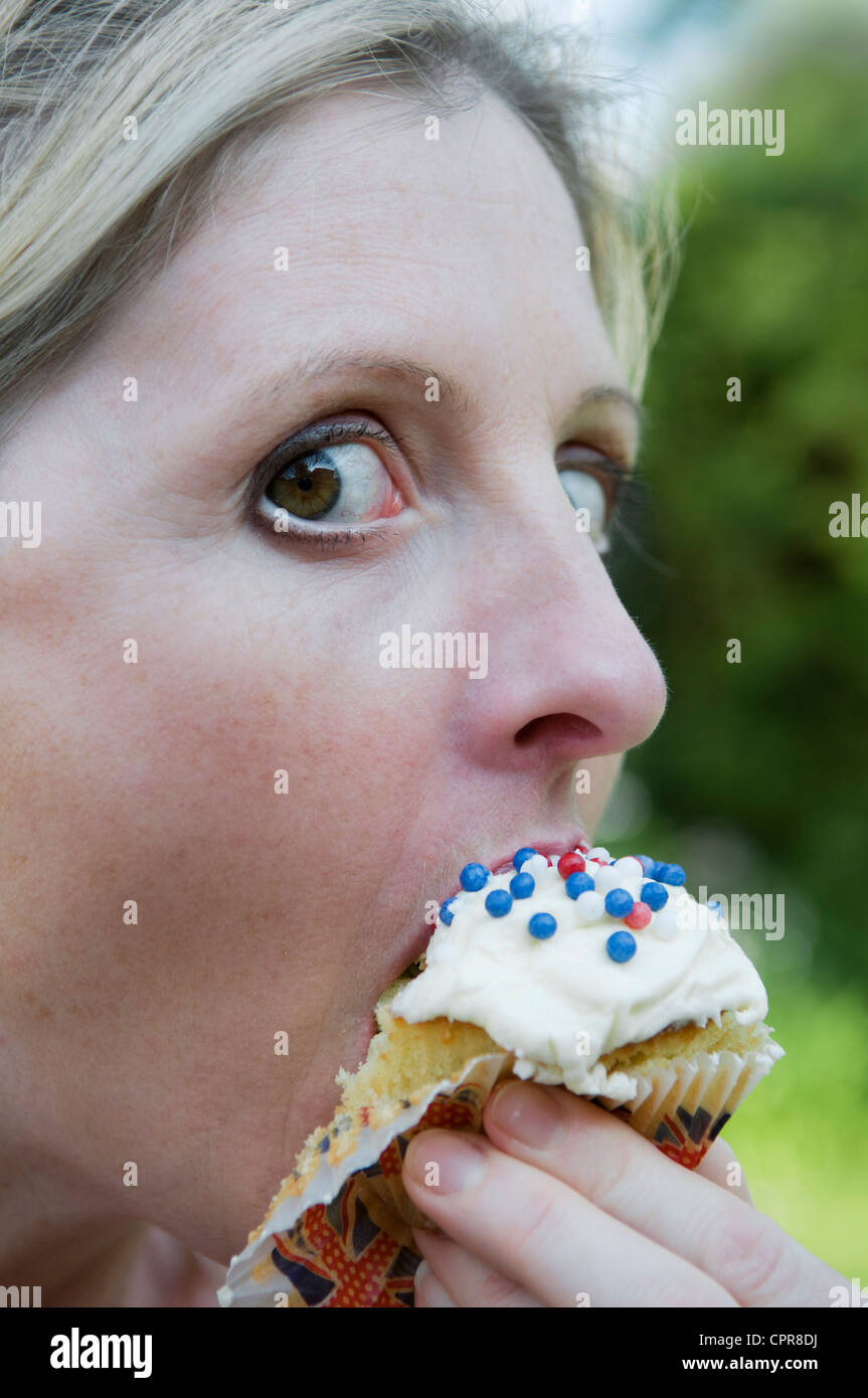 Closeup of woman eating cupcake with eyes wide in surprise. concept of ...