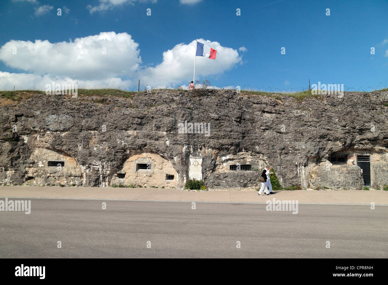 A couple walk in front of the concrete structure of Fort Vaux, located ...