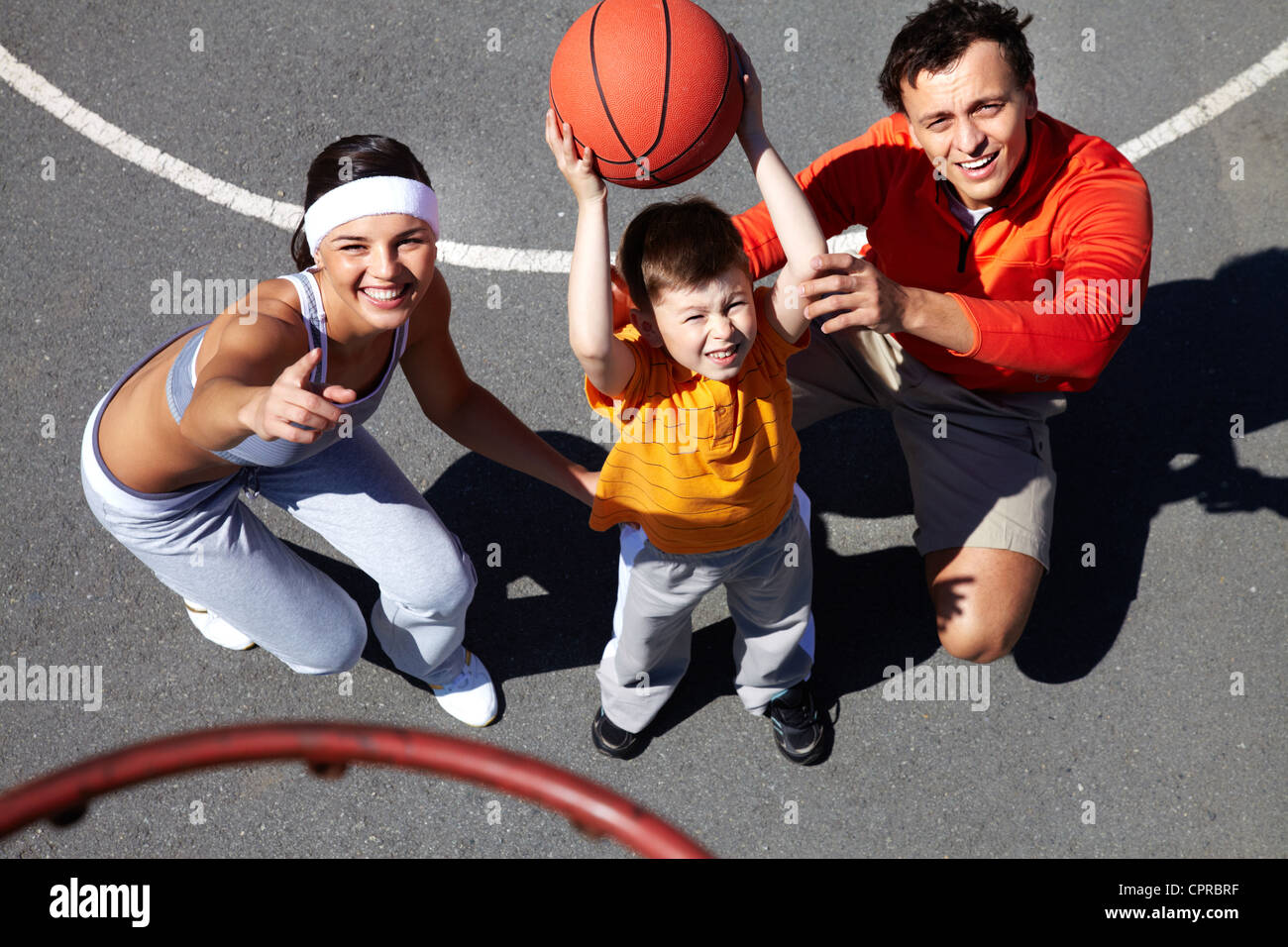 Image of parents showing their son how to throw ball into basket Stock ...