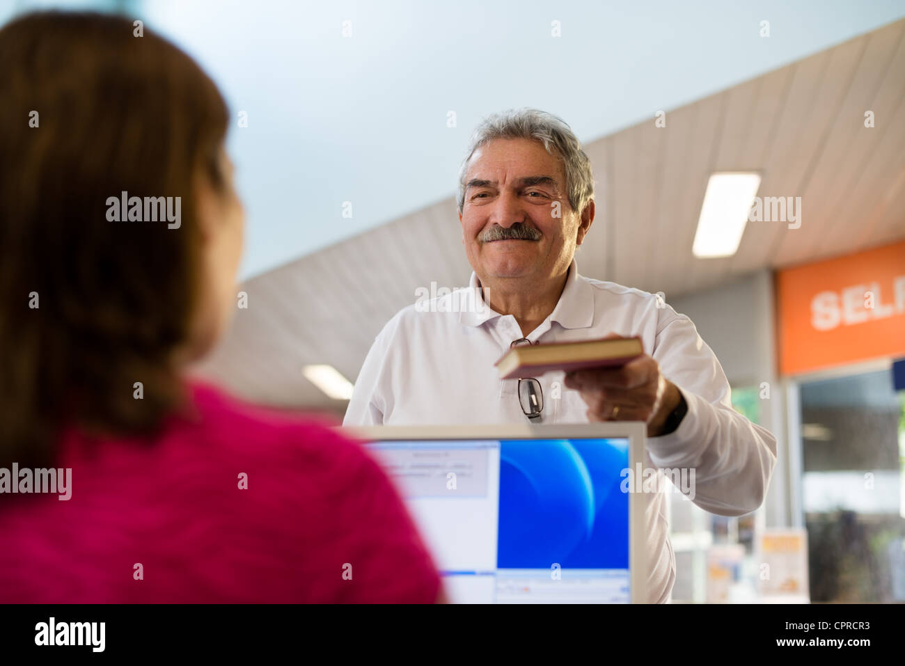 Portrait of young woman and happy old retired man returning book to ...