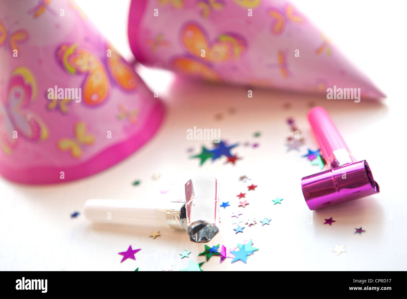 Party hats and tooters on a white background with star shaped confetti ...