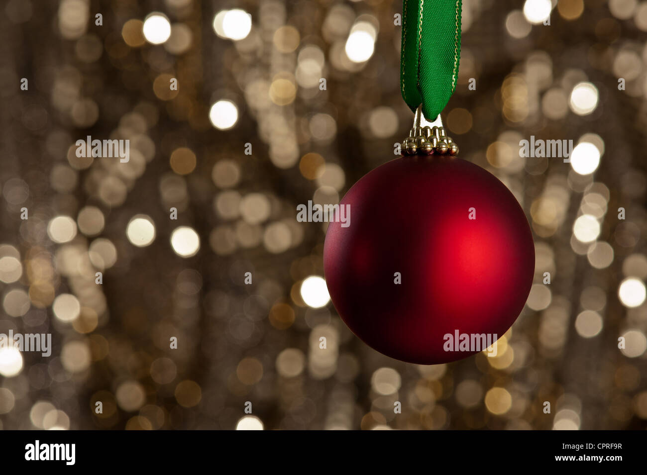 Single red Christmas bauble in front of a gold glitter background for ...