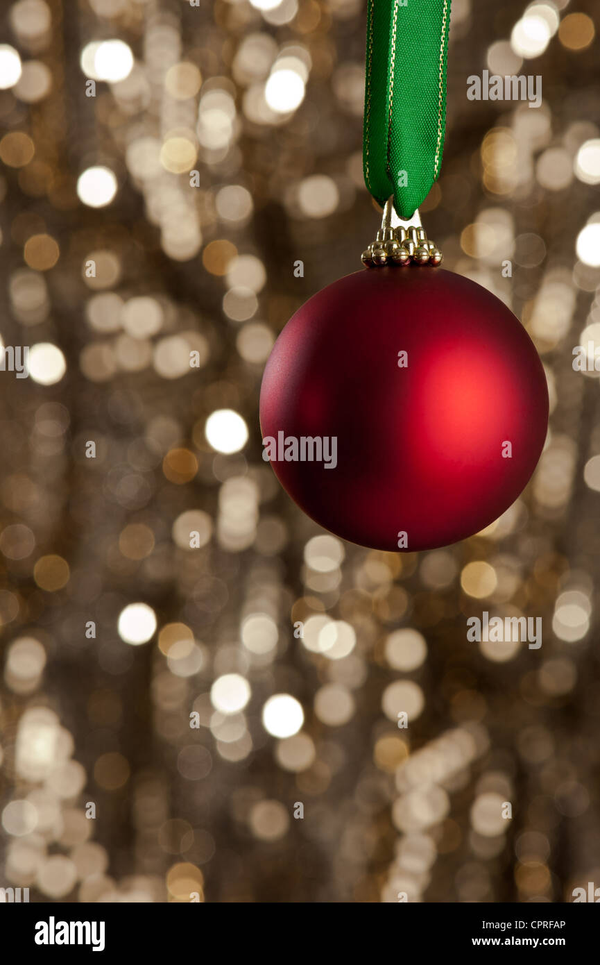 Single red Christmas bauble in front of a gold glitter background for ...