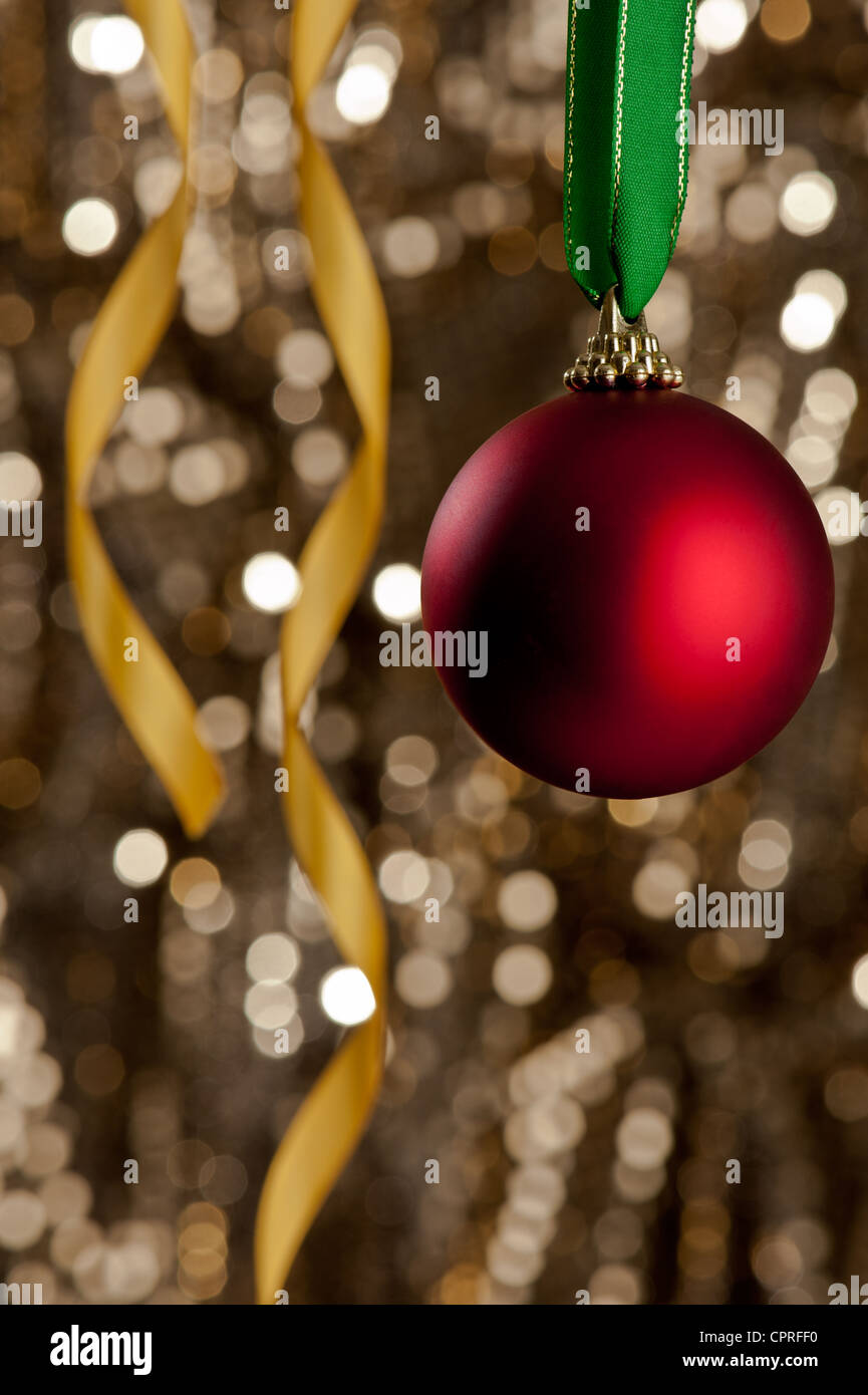 Single red Christmas bauble in front of a gold glitter background for ...
