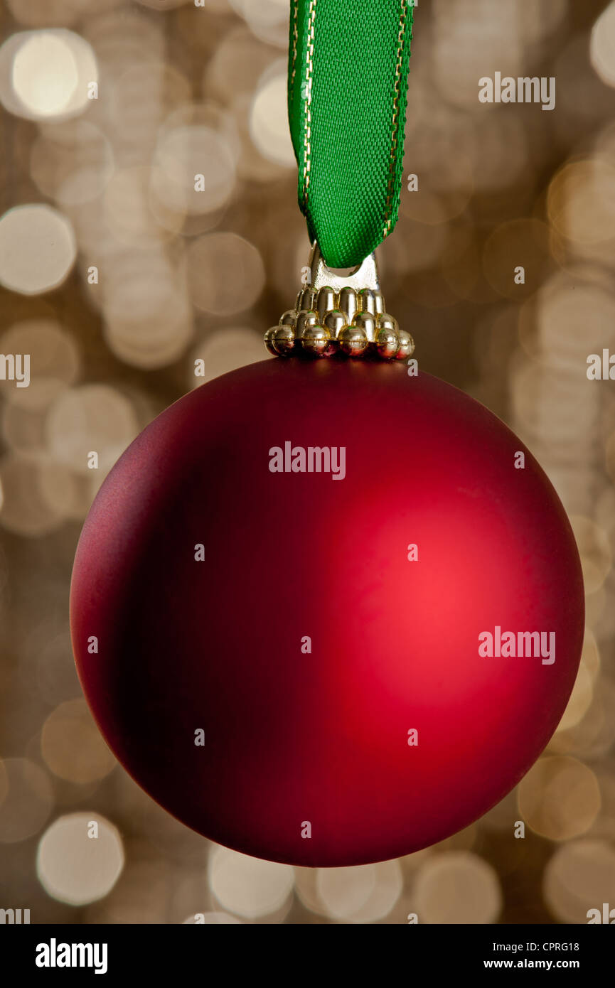 Single red Christmas bauble in front of a gold glitter background for ...