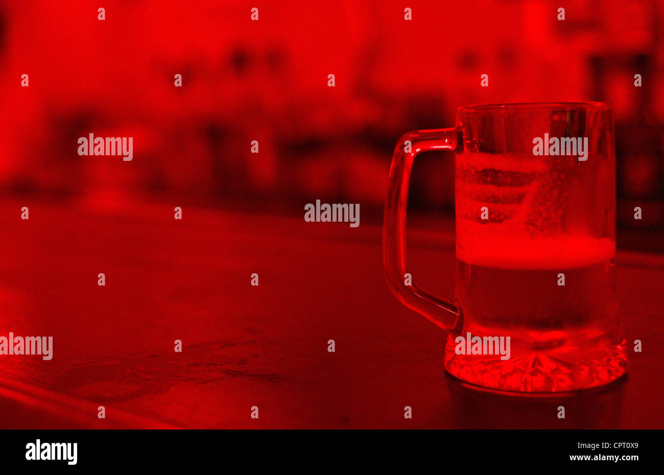 Half-empty beer glass on bar in orange light Stock Photo - Alamy