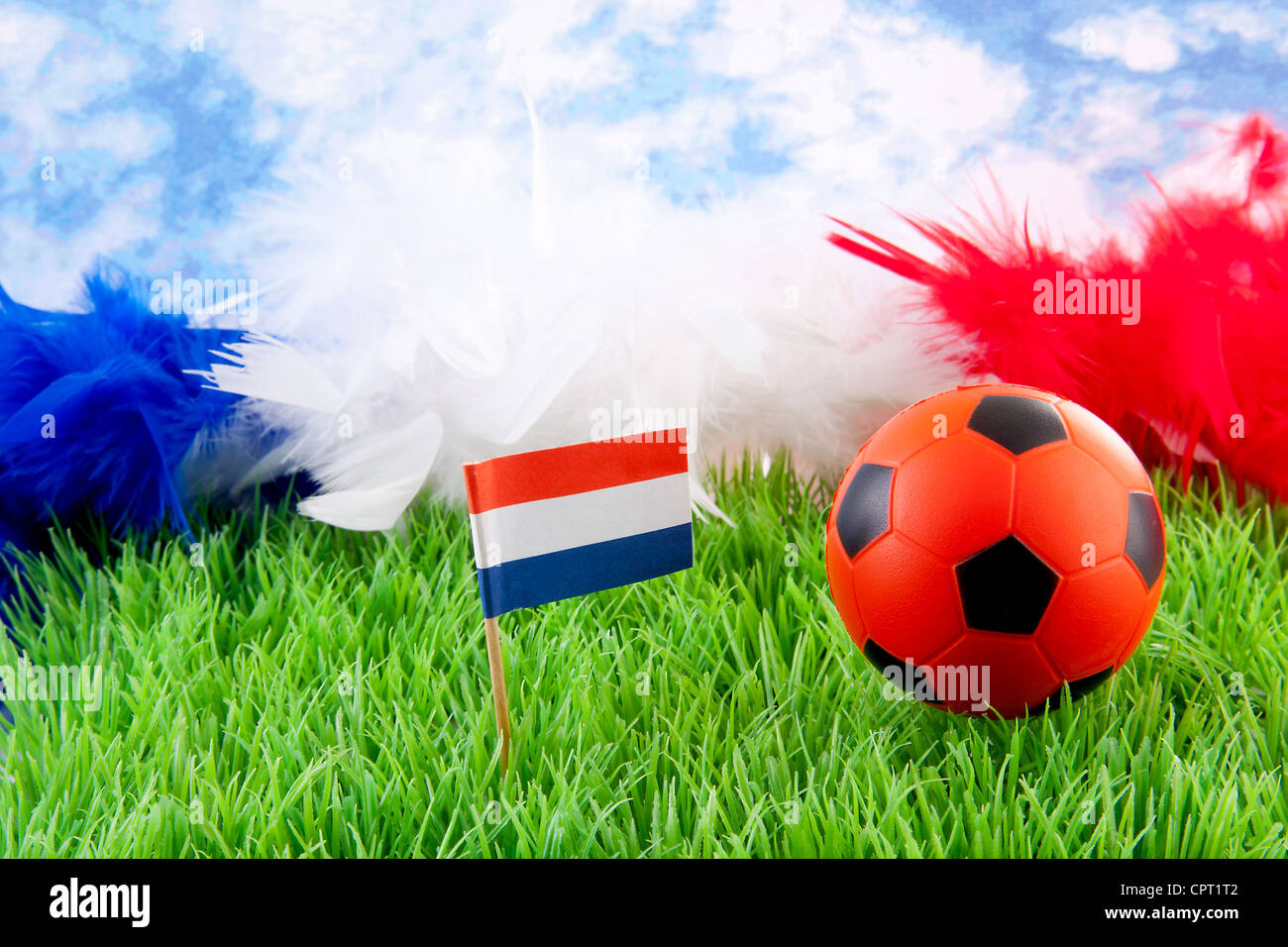 orange Soccer ball and Dutch flag on grass against blue cloudy sky ...