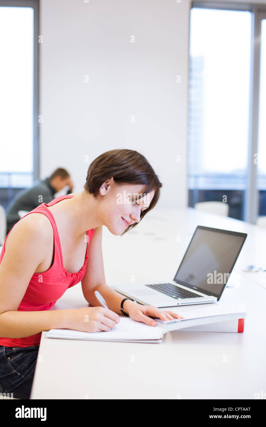 Pretty young college student studying in the library/a study room at ...