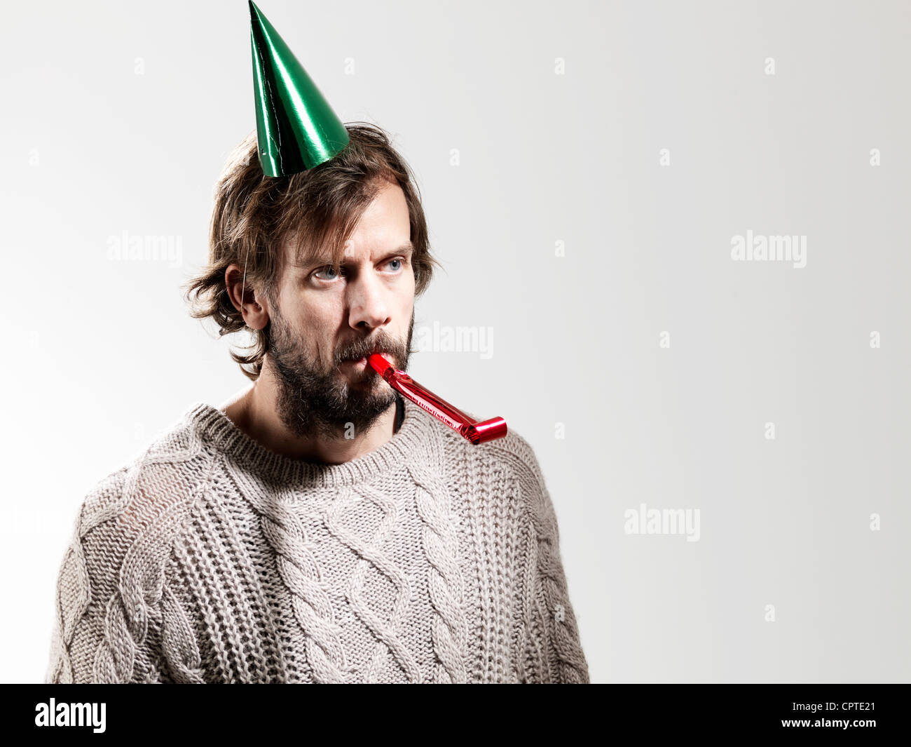 Mid adult man with party blower against white background Stock Photo ...