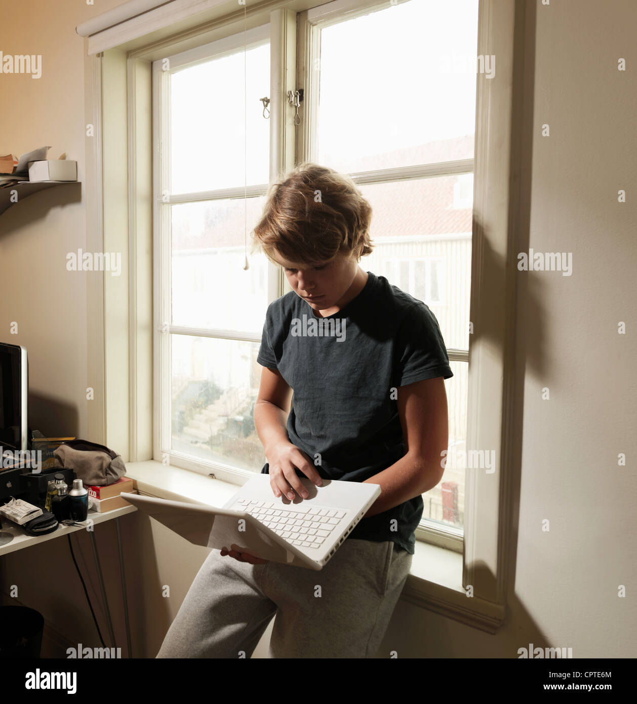 Teenage boy using laptop in room Stock Photo - Alamy