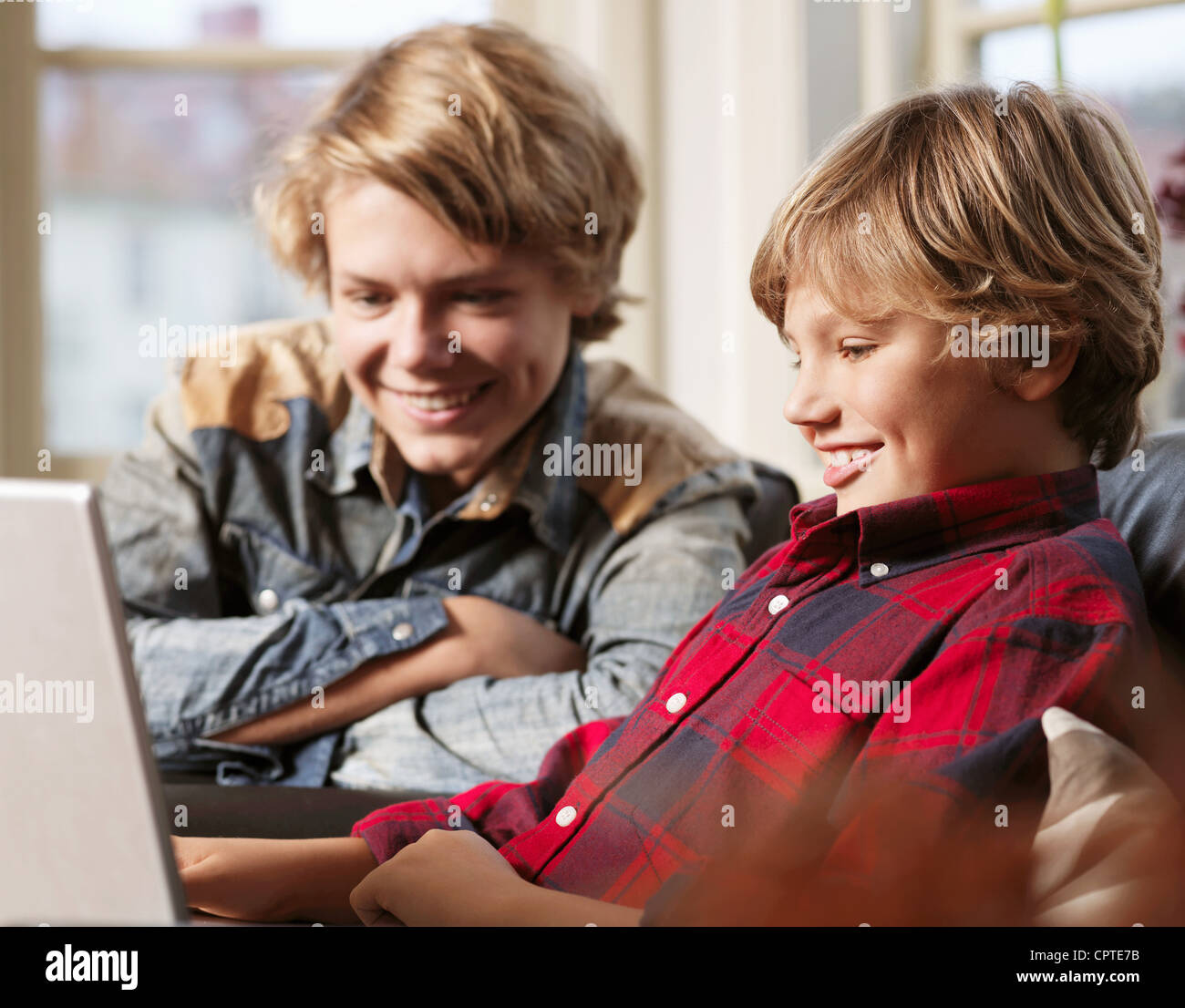 Teenage boy and brother watching laptop Stock Photo - Alamy