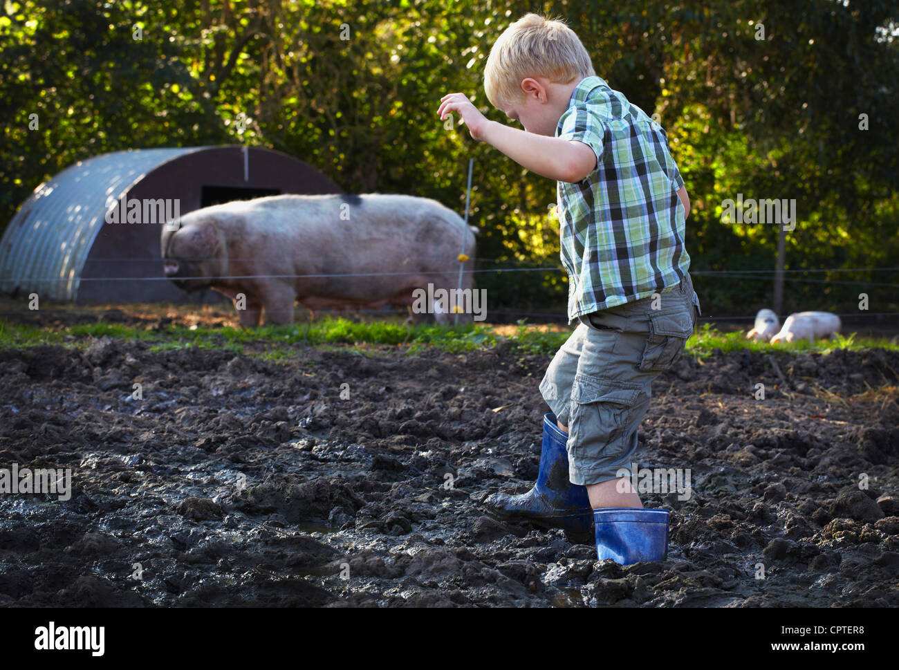 Young boy walking through mud Stock Photo - Alamy