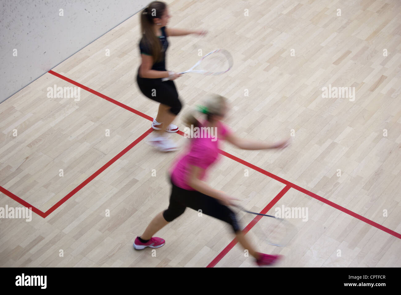 Two female squash players in fast action on a squash court (motion ...
