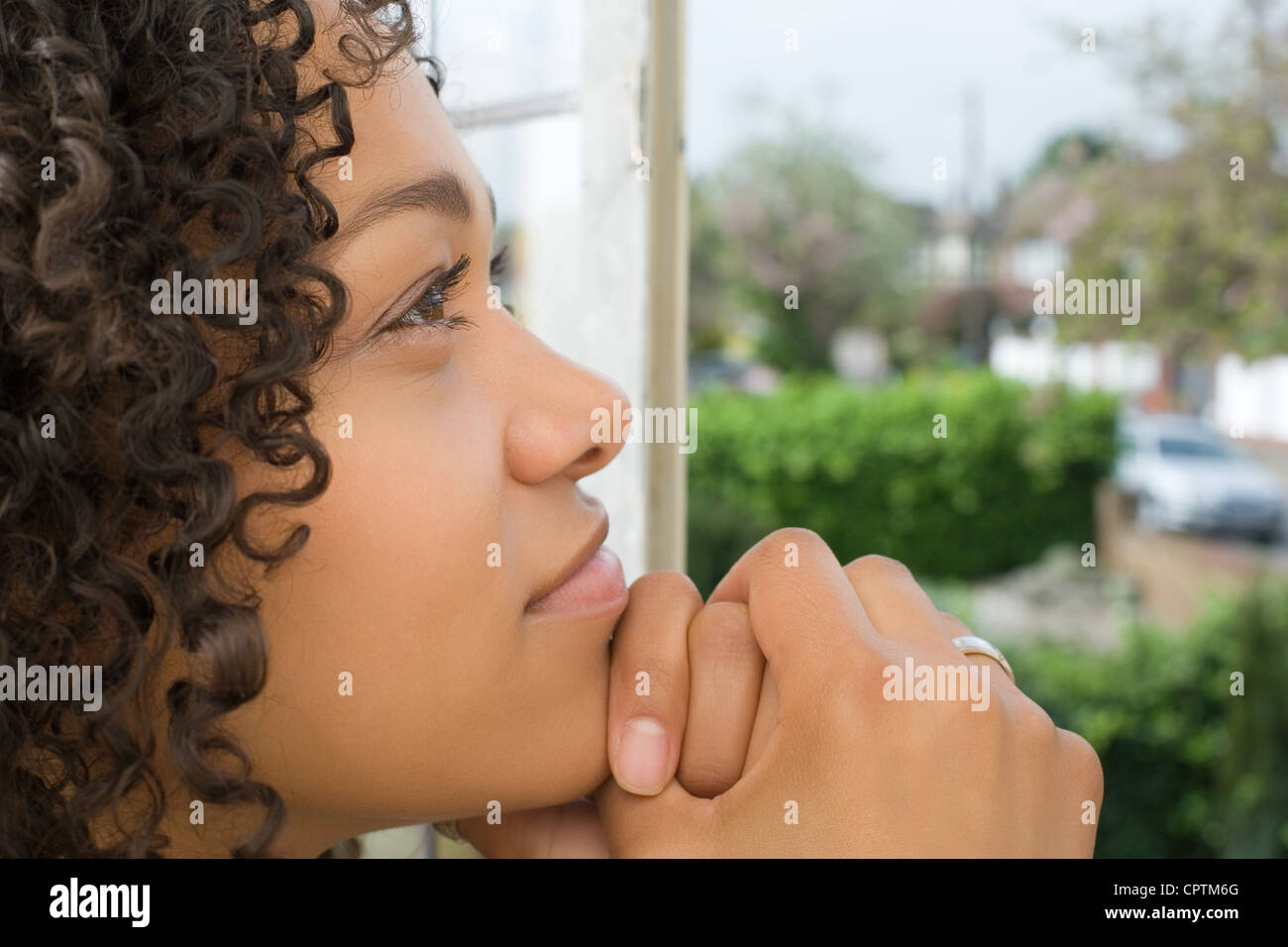 Portrait of a young woman looking out of a window Stock Photo - Alamy