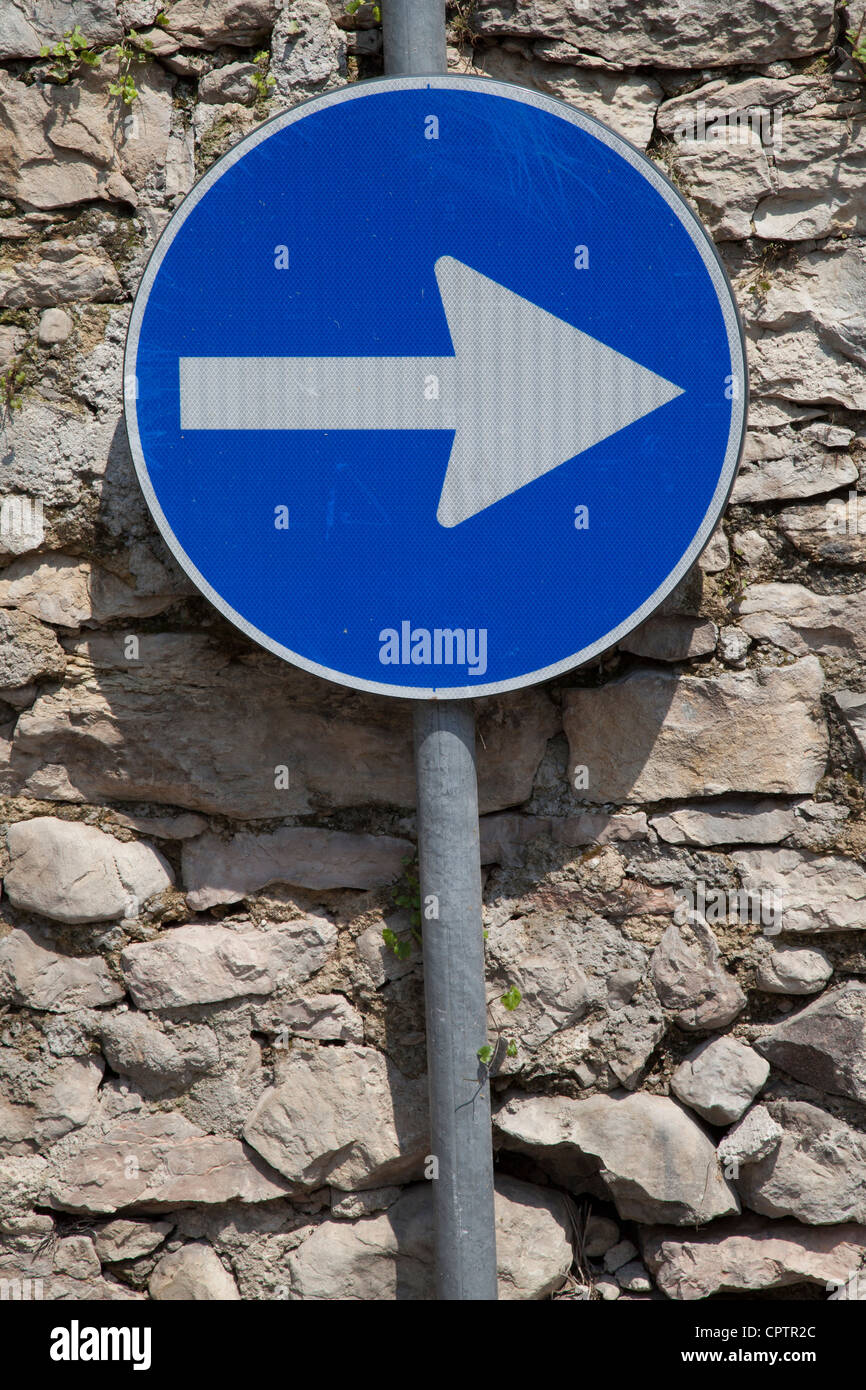 A road sign pointing the direction up a mountain road in Lake Garda ...